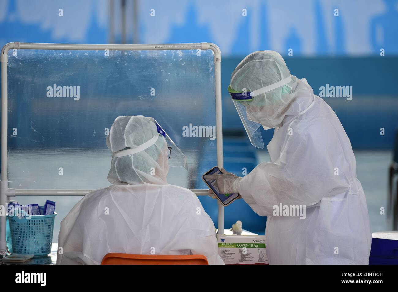 A public health worker wearing PPE uniform providing rapid antigen ...