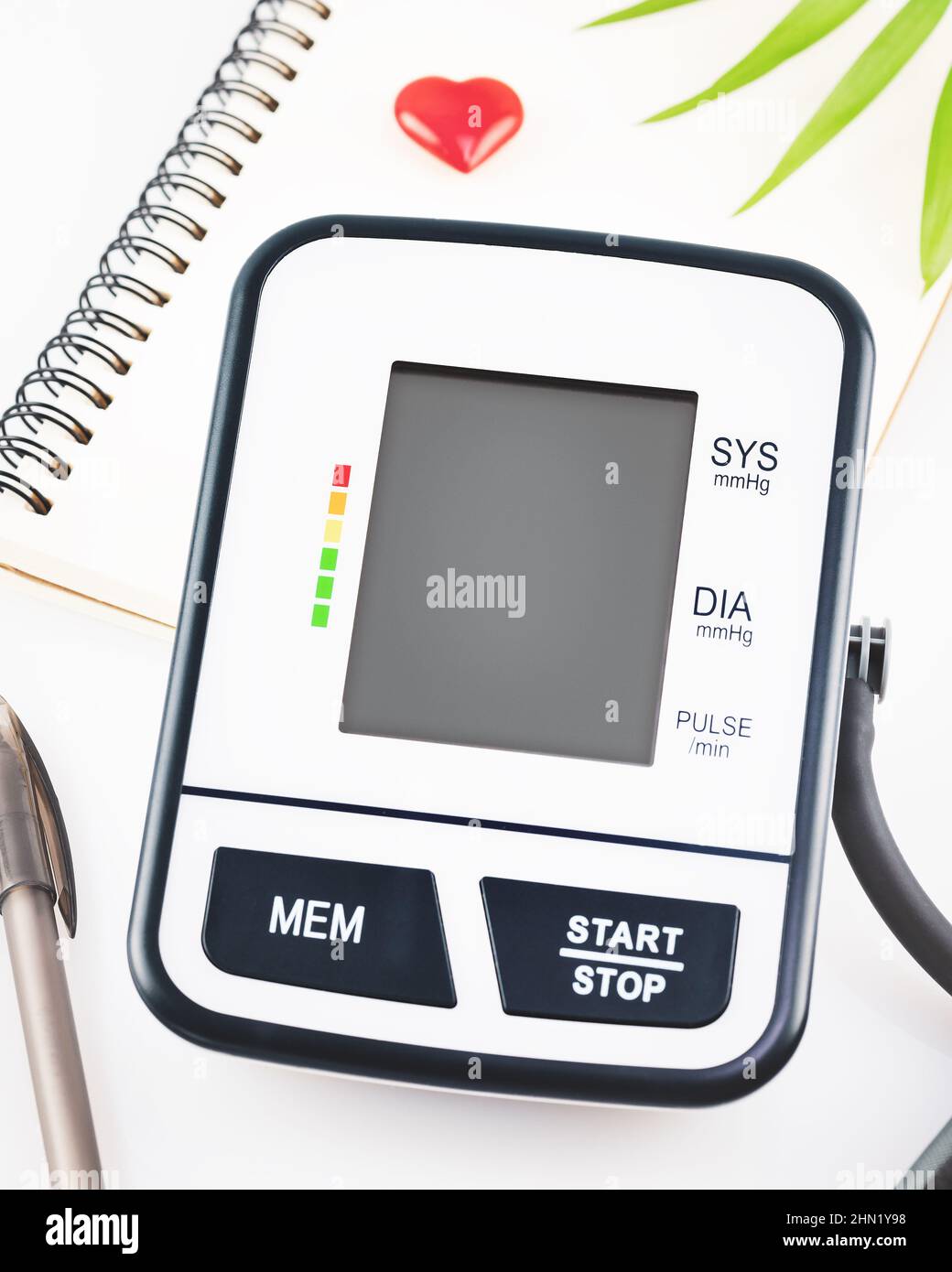 Digital blood pressure monitor, notepad, pen on a white background with ...