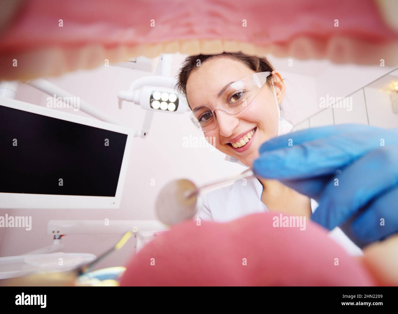 pretty young female dentist examines the patient's teeth. View from ...