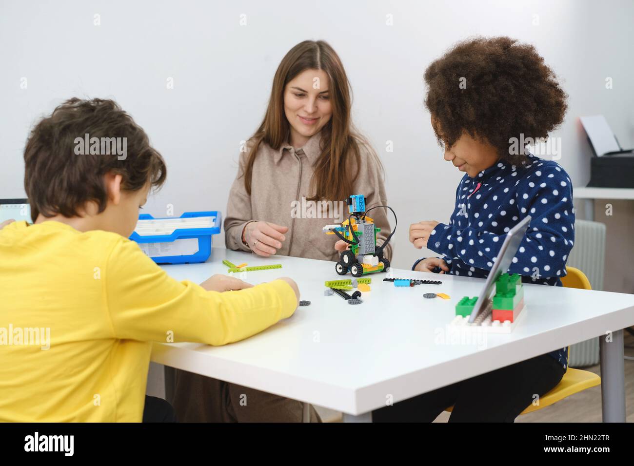 Multiethnic kids at STEM lesson constructing robot in classroom with ...