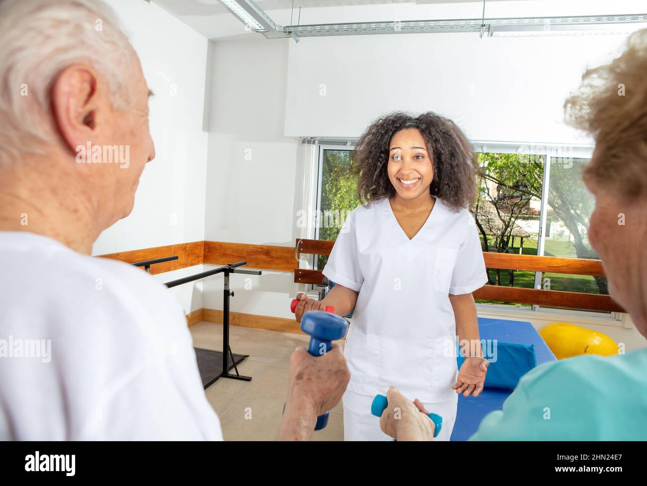 Happy couple of seniors smiling training at the gym helped by african ...