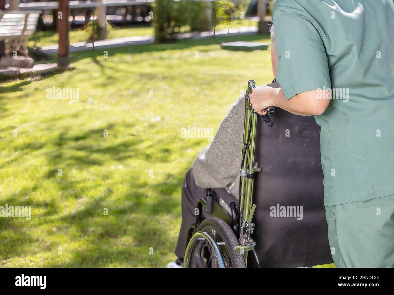 Caucasian senior on the wheelchair helped by nurse outdoor. Retired ...