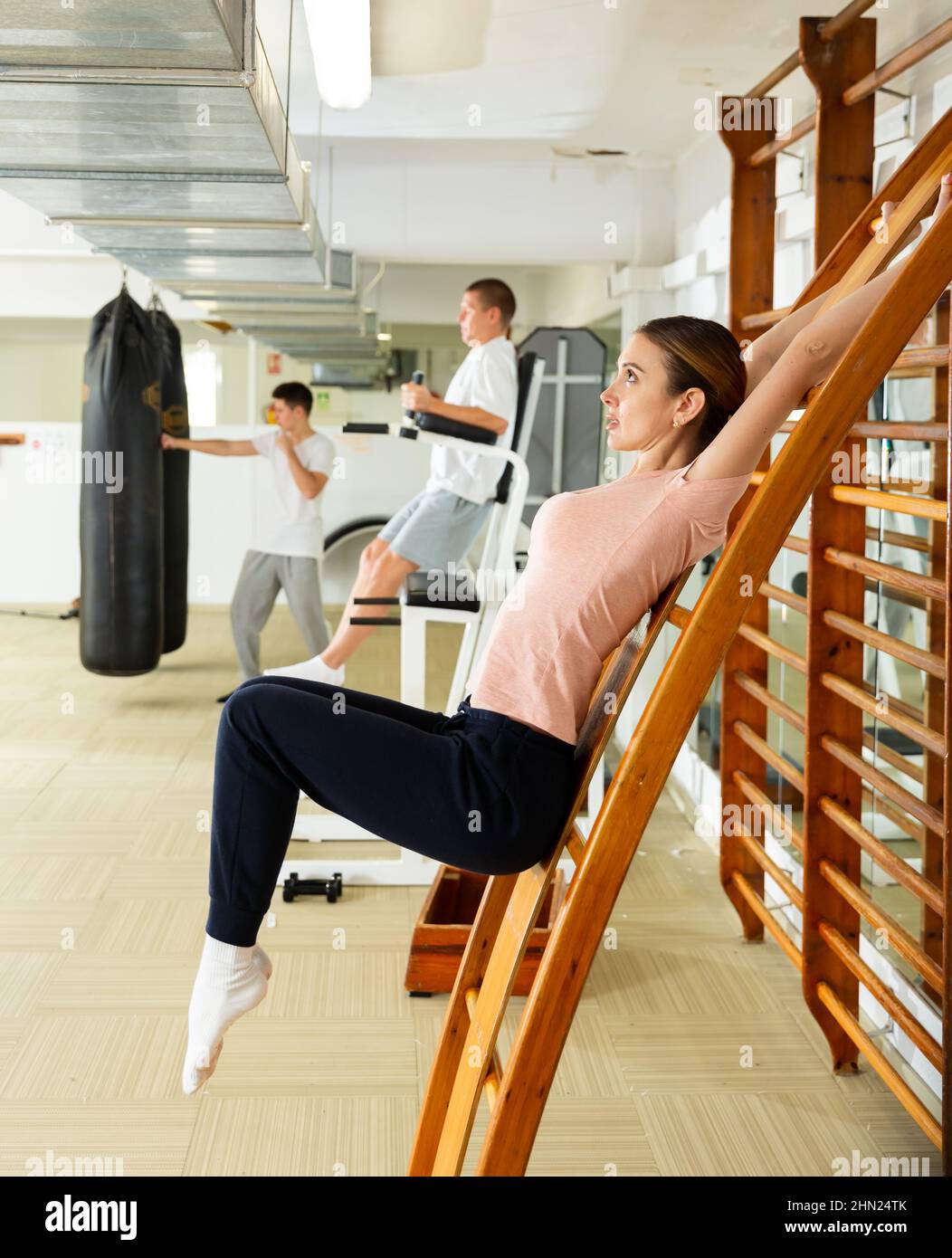 Young woman performing leg raises on wall bars in gym Stock Photo - Alamy