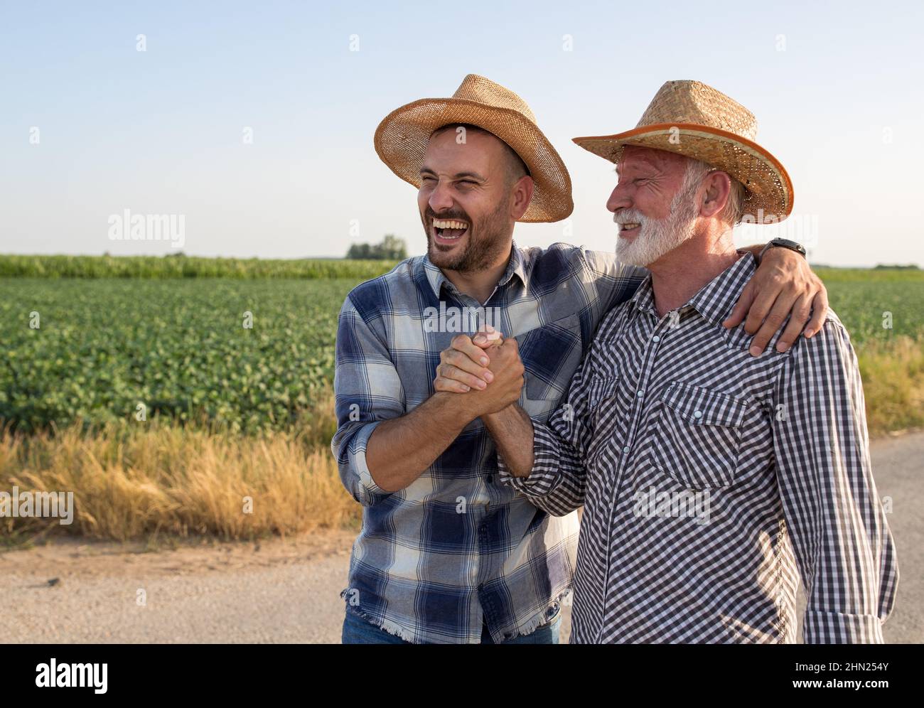 Two farmers laughing, hugging and smiling in field during harvest in ...