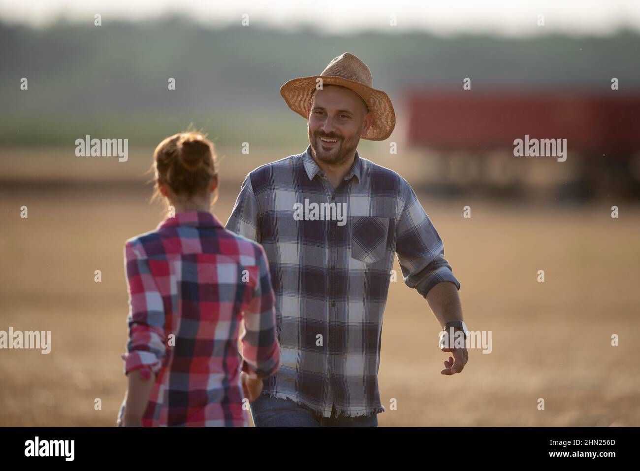 Two farmers man and woman talking in field during harvest in summer ...