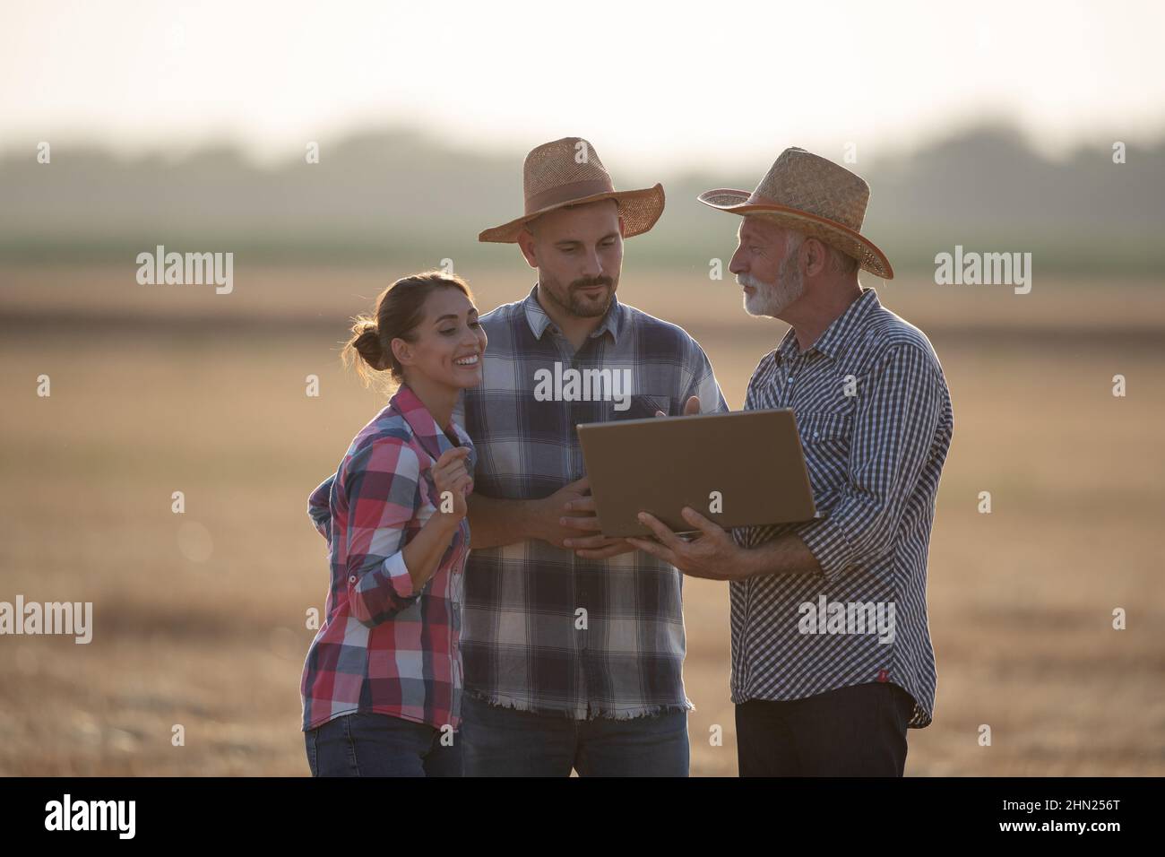 Senior experienced farmer with laptop explaining something to younger ...