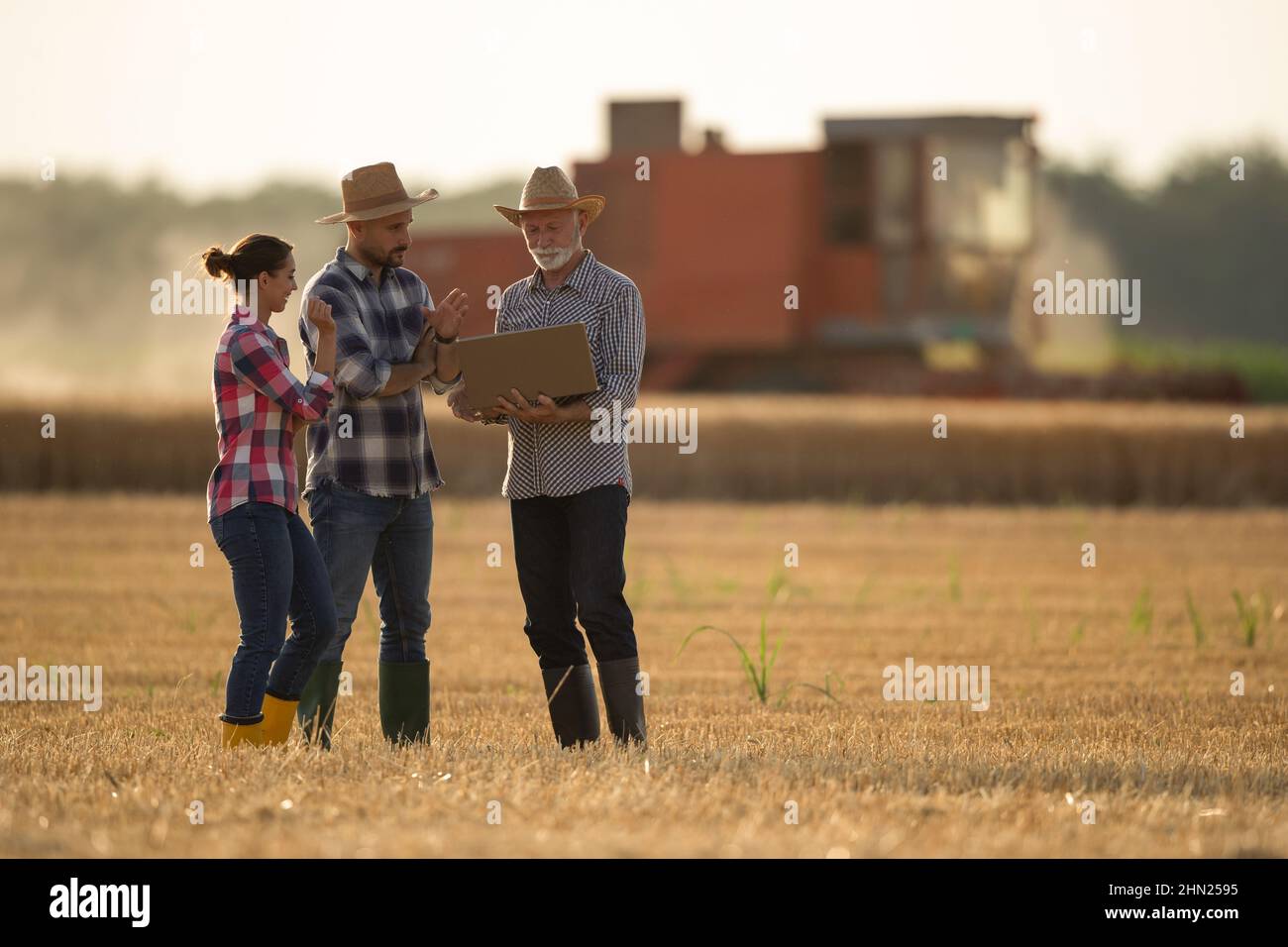 Senior experienced farmer with laptop explaining something to younger ...