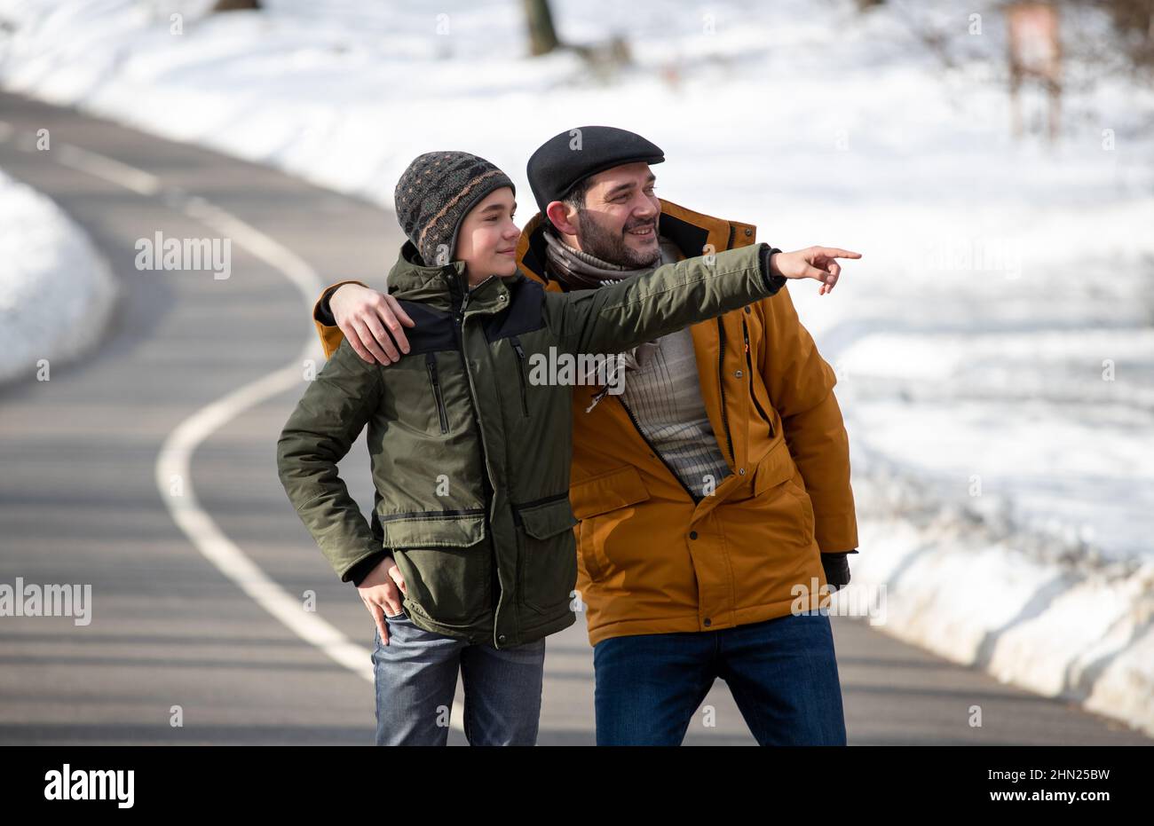 Happy son pointing finger to something to his father while they ...