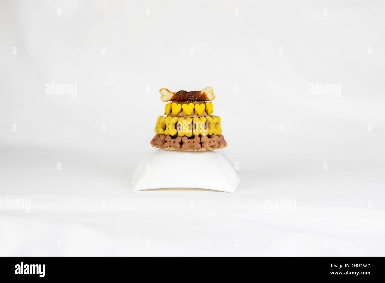 A cake for a dog stands on a white stand on a white background. A three ...