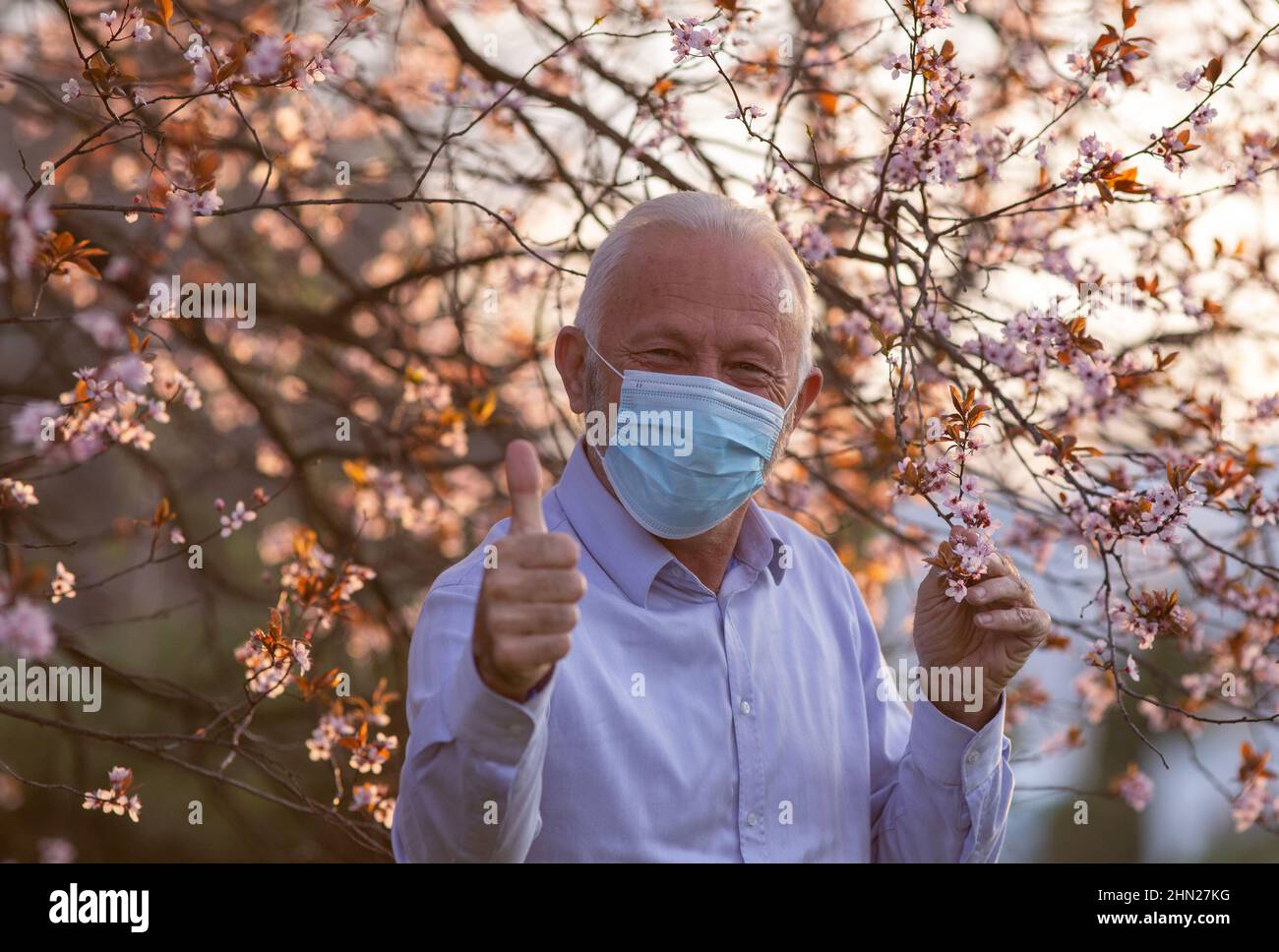 Senior man wearing protective mask and showing thumb up in front of ...