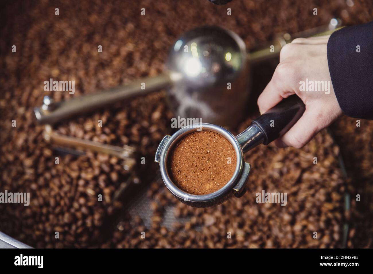 Close up girl hand holding a portafilter with ground coffee. Barista ...