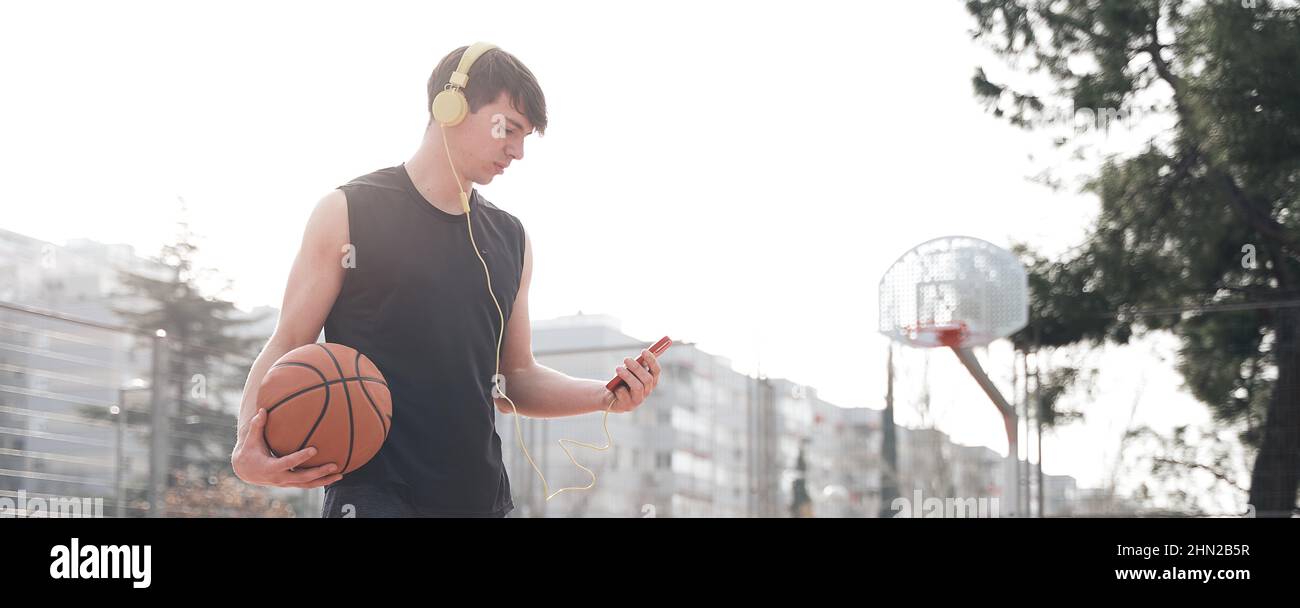 young athlete on a basketball court training while listening to music ...