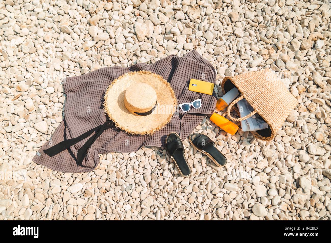 overhead view of beach stuff blanket with sun protection cream straw ...