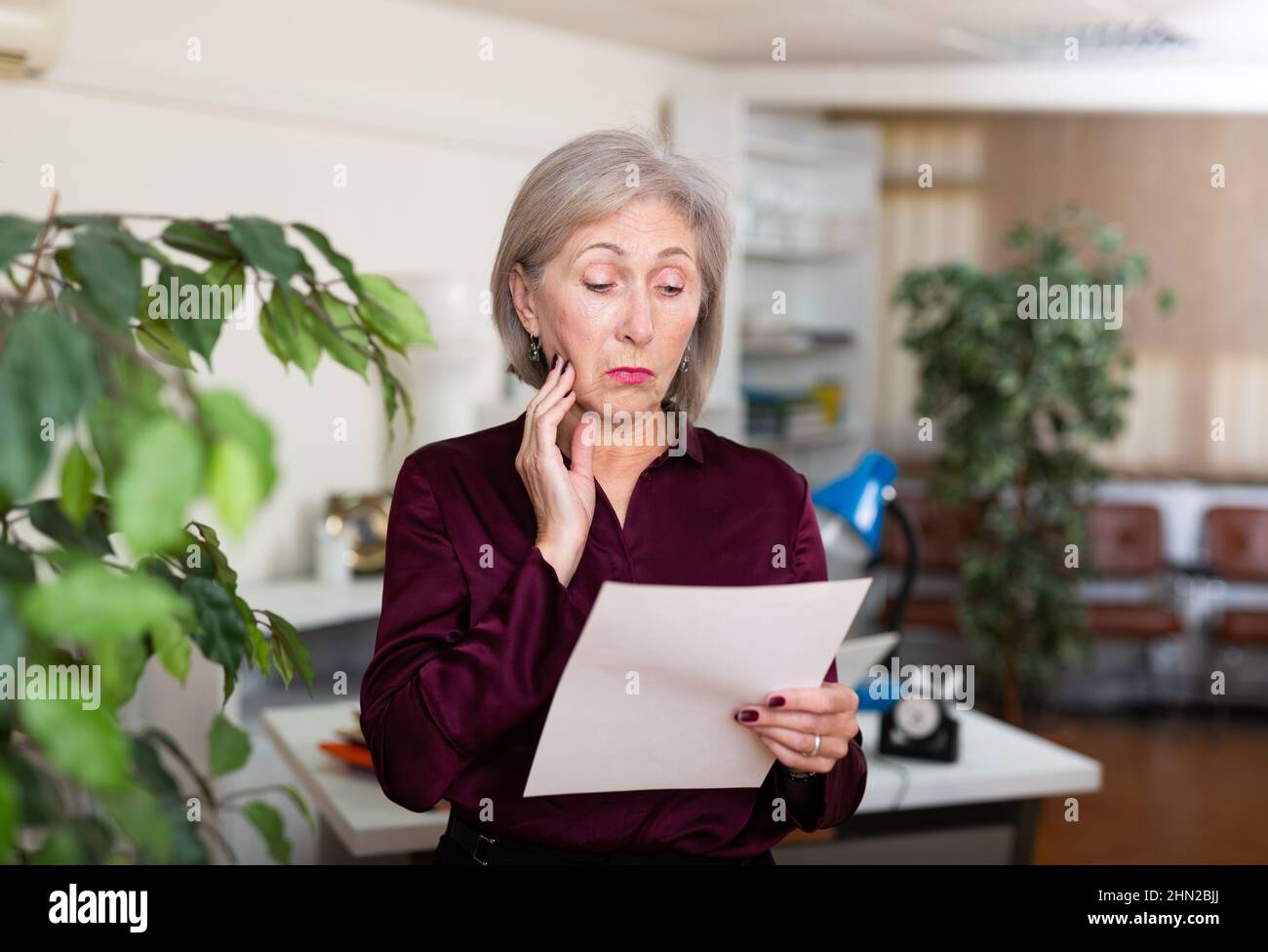 Upset mature woman standing in office Stock Photo - Alamy