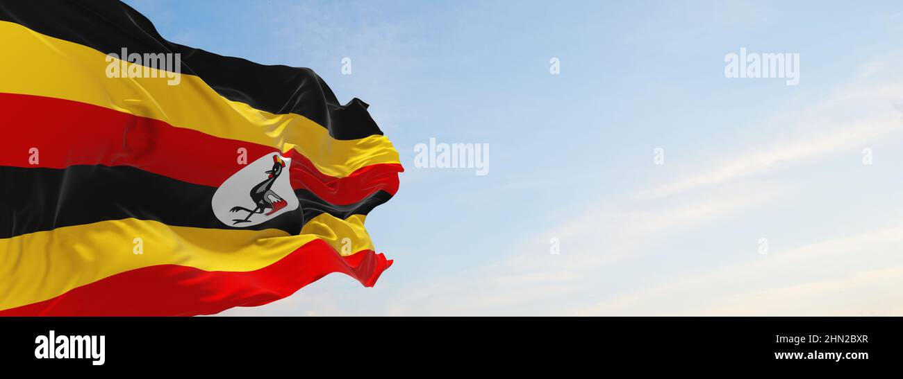 official flag of Uganda at cloudy sky background on sunset, panoramic ...