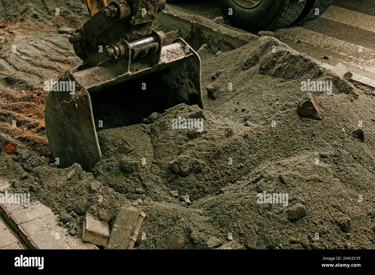 Road works on the city street. The excavator bucket collects the old ...