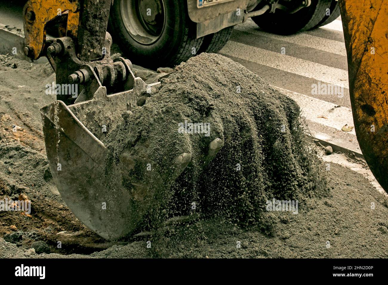 Road works on the city street. The excavator bucket collects the old ...