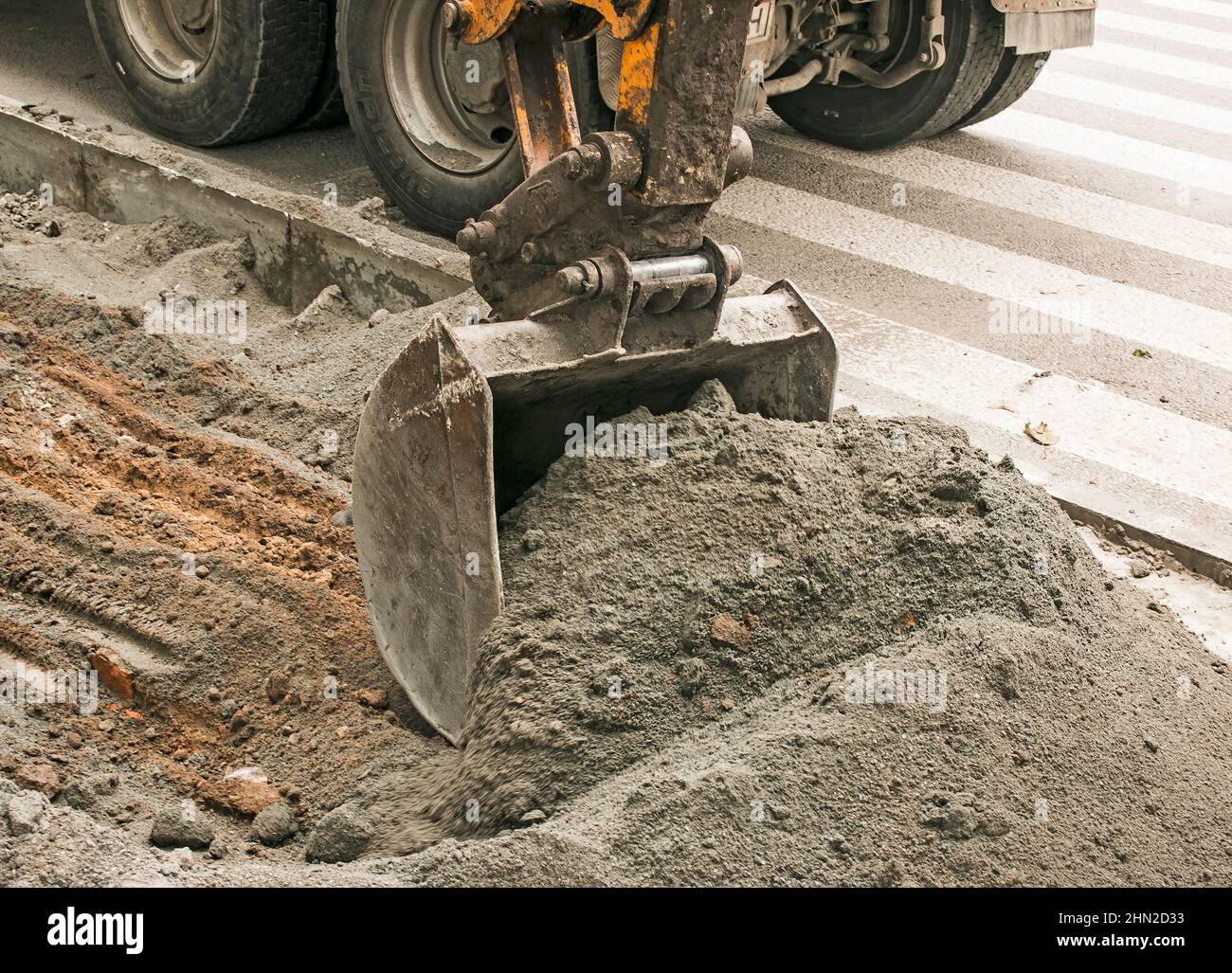 Road works on the city street. The excavator bucket collects the old ...