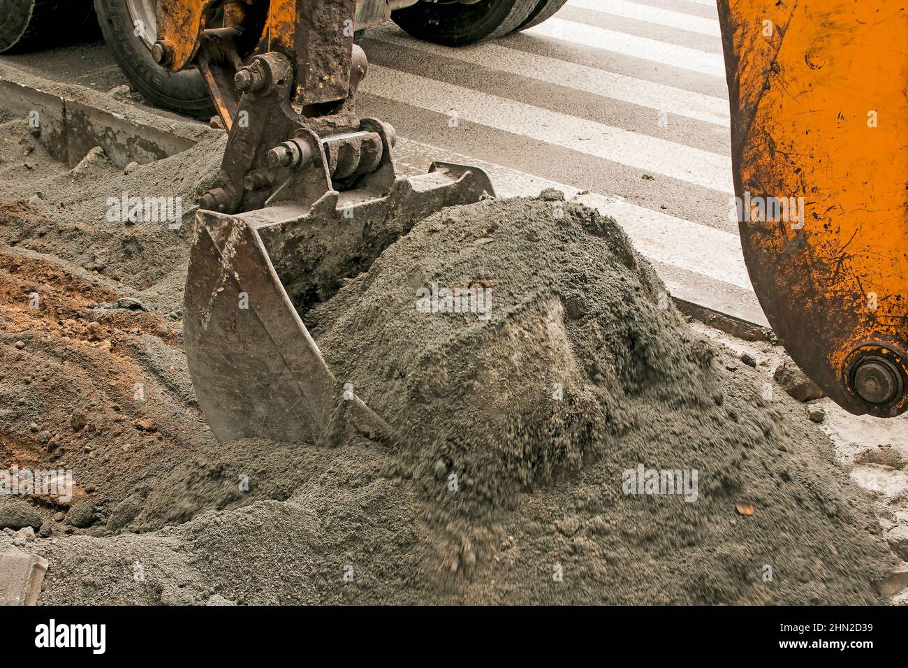 Road works on the city street. The excavator bucket collects the old ...