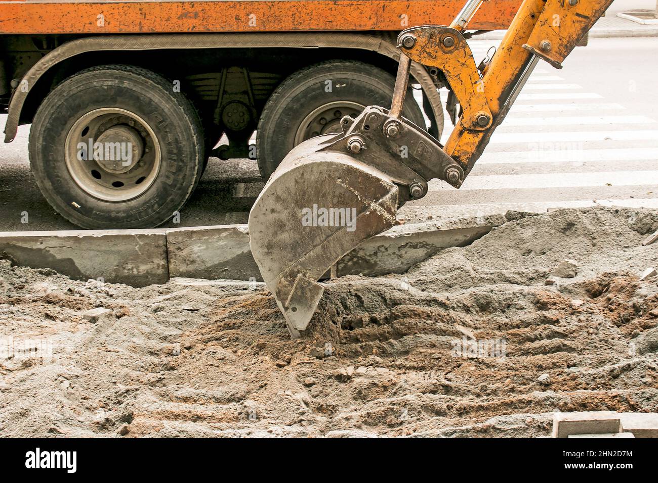 Road works on the city street. The excavator bucket collects the old ...