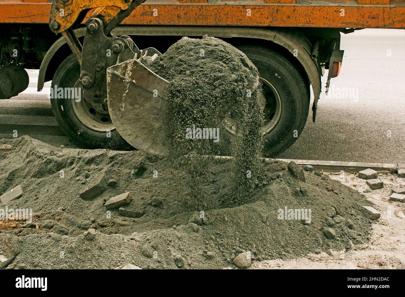 Road works on the city street. The excavator bucket collects the old ...