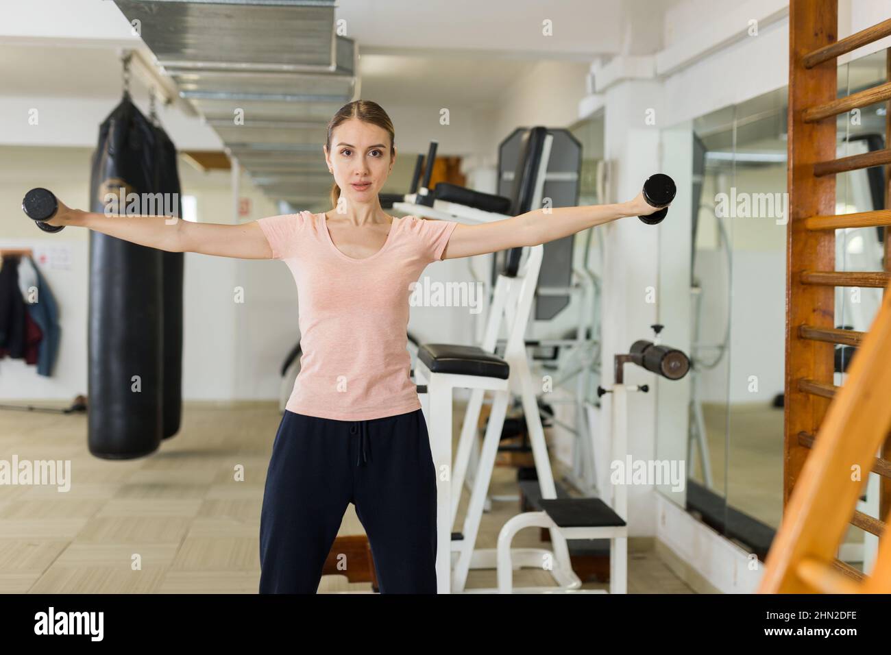 Sporty girl working out arms muscles with dumbbells in gym Stock Photo ...