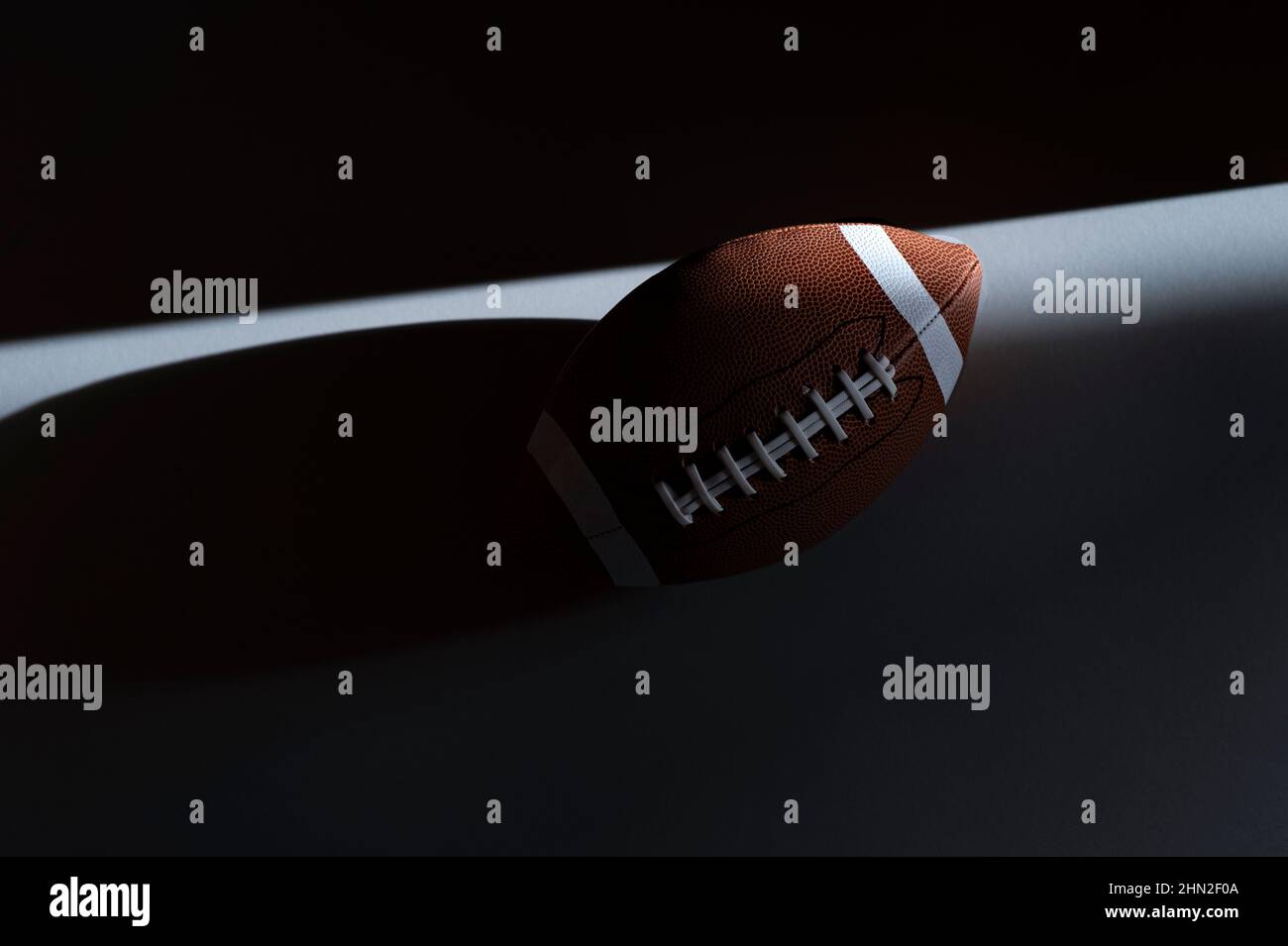 American football ball with natural lighting on dark background ...