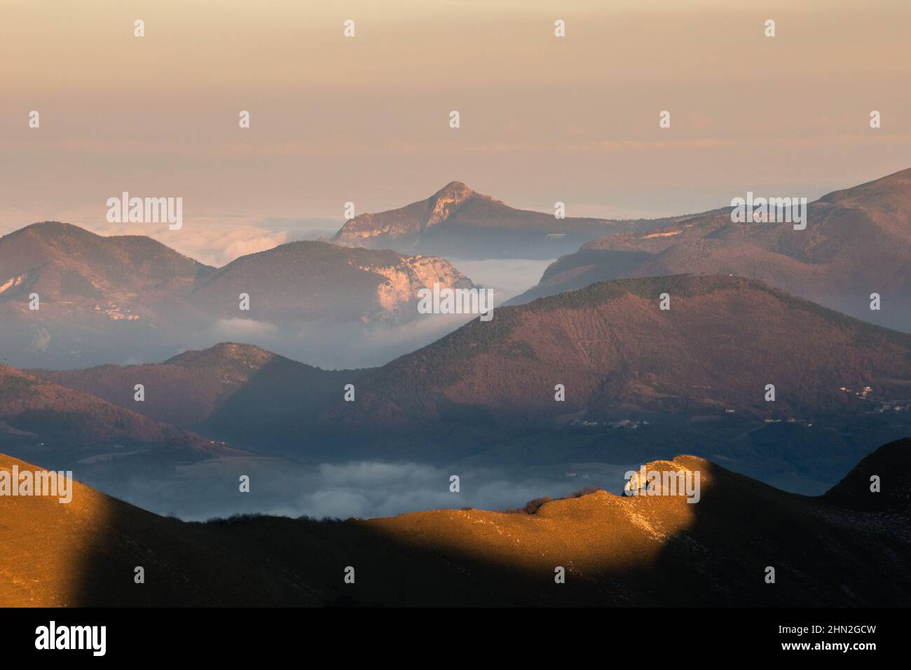 Mist and fog between valley and layers of mountains and hills at sunset ...