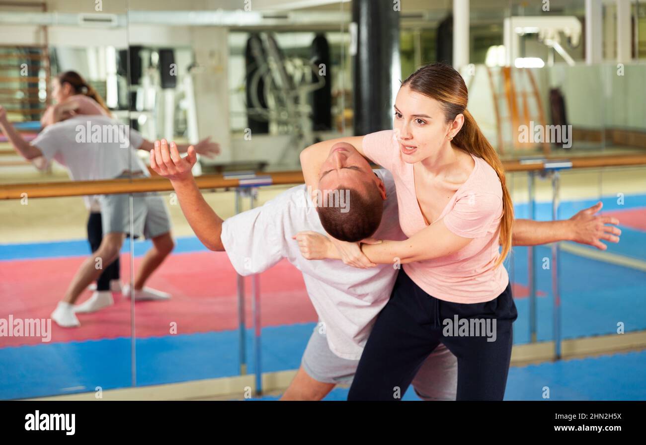 Young woman practicing inverted facelock on male opponent in gym Stock ...