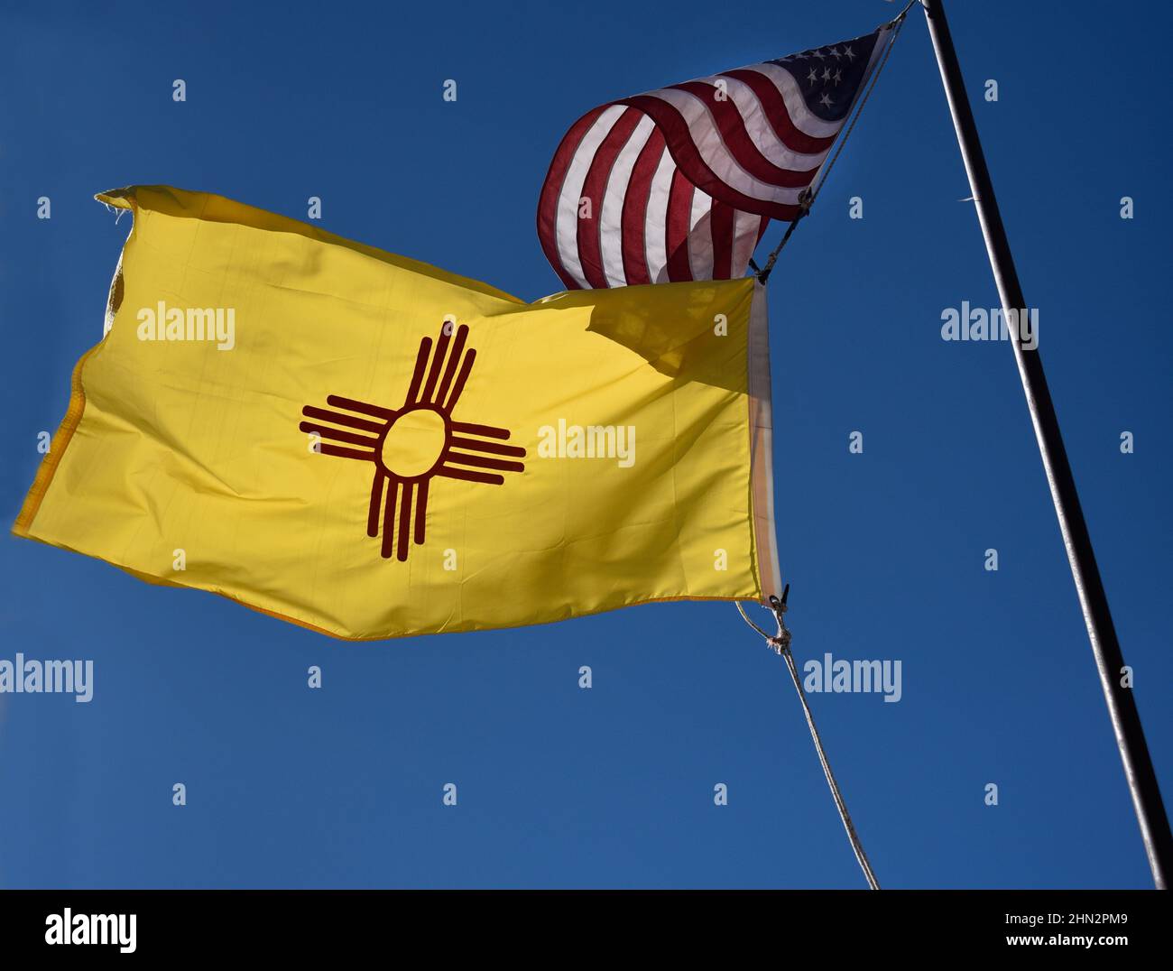 A New Mexico state flag flies below a United States flag in Santa Fe ...