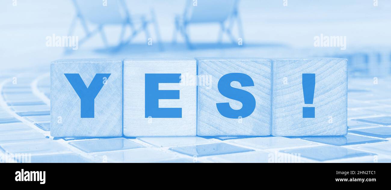 The word Yes written in black letters on wooden blocks in ocean ...