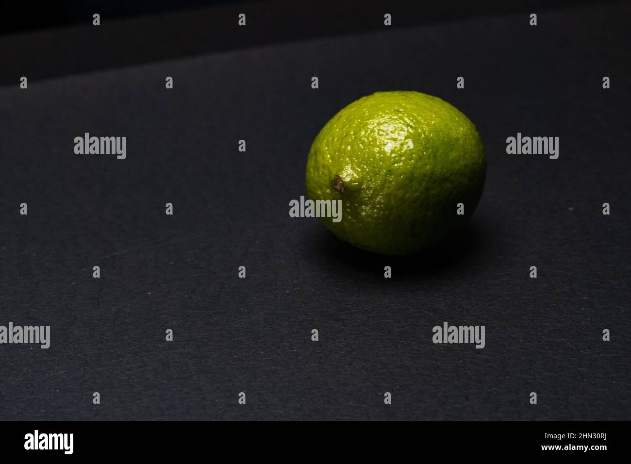 lime raw lemon tree branch hanging and black background Stock Photo - Alamy