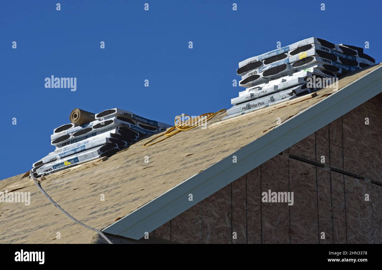Bundles of roofing tiles are piled up on the roof of a house under ...