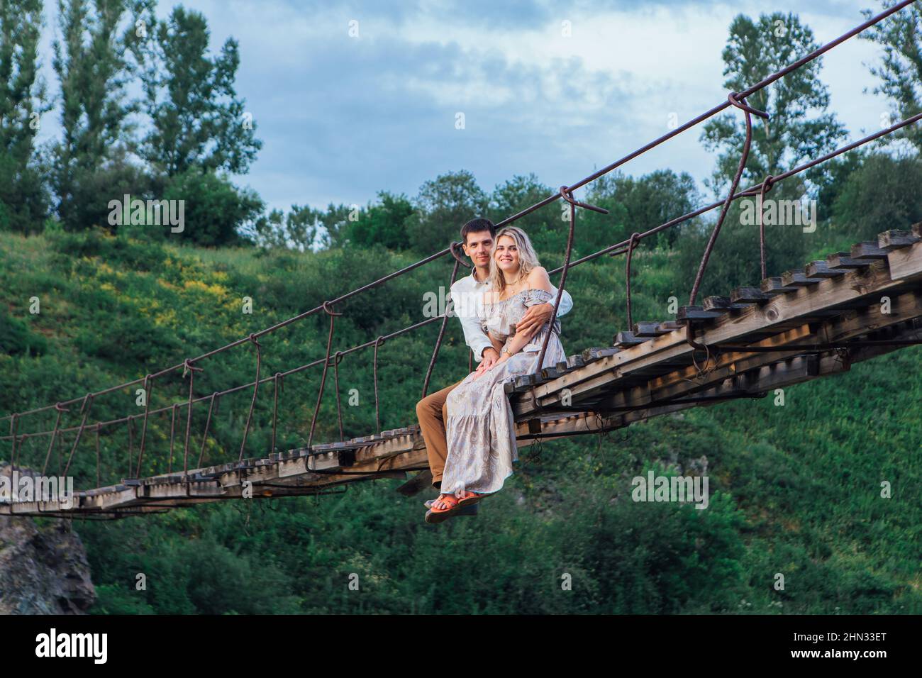 Beautiful young romantic couple sitting and hugging on the suspension ...