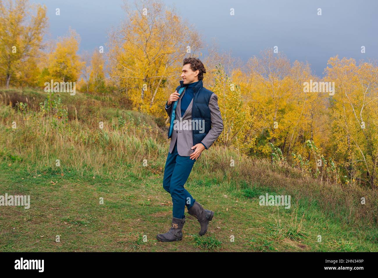 Tall handsome man walking outdoor in yellow autumn forest on the hill ...