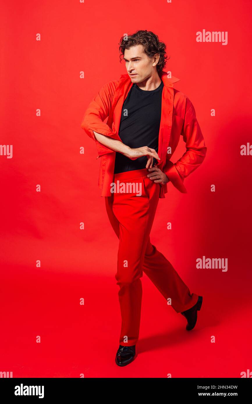 Portrait of a tall handsome man dressed in red shirt posing on the red ...