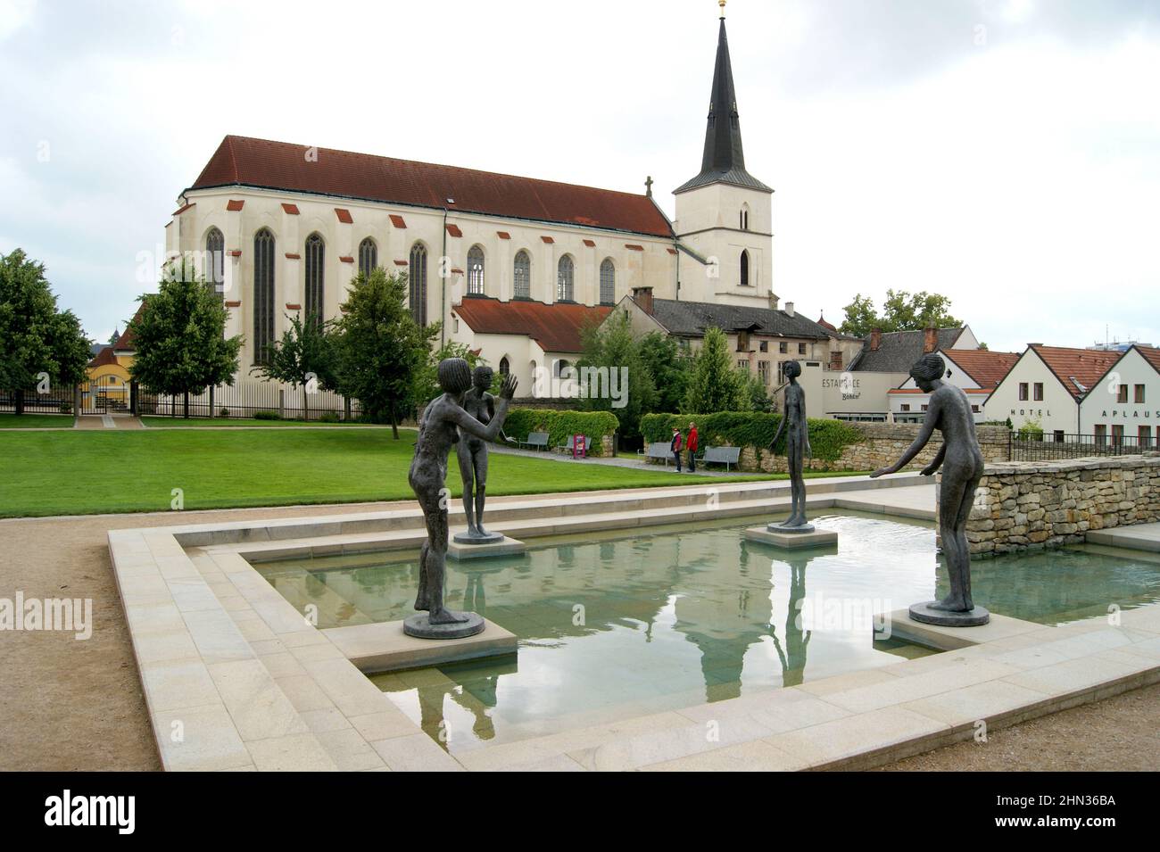 Water pool with modern open air sculptures, gothic and baroque Church ...