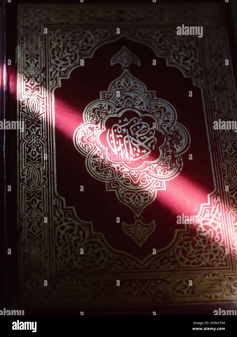 Sun light ray at cover of red quran holy book for muslim prayers ...