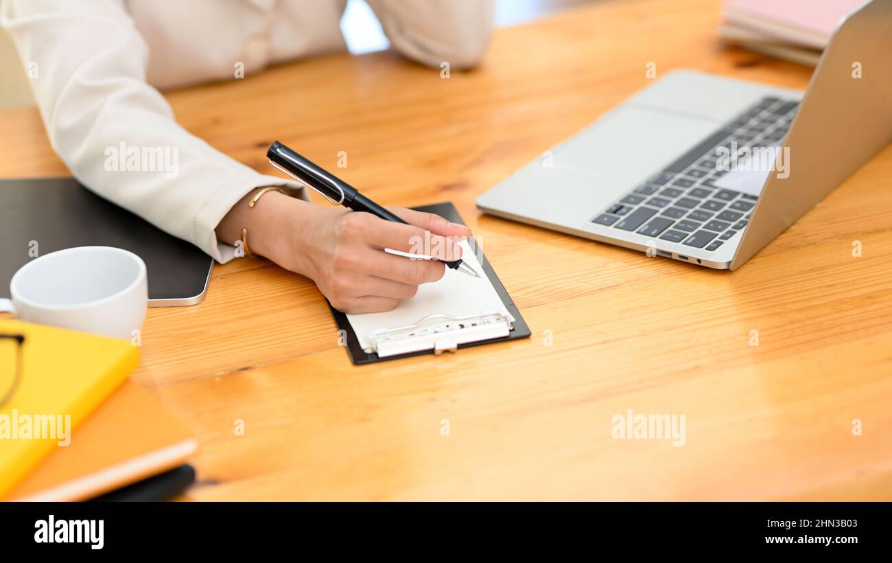 Close-up image, A businesswoman taking notes on notepad with pen on her ...