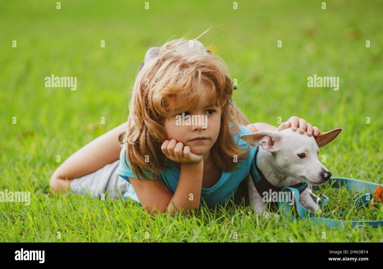 Boy lying on grass with dog. Happy puppy owner child playing with doggy ...