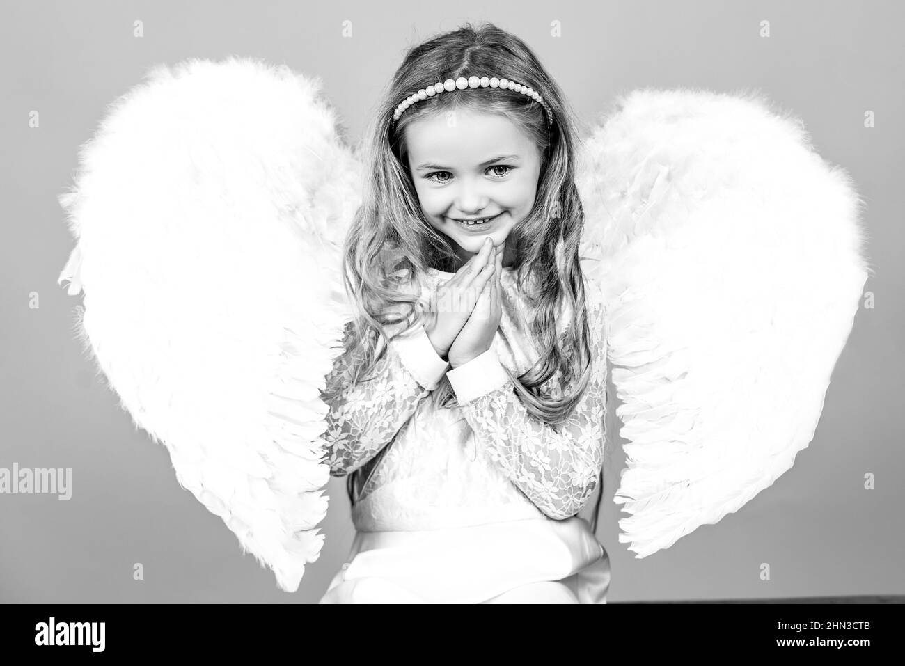 Beautiful little angel girl standing with your arms close to your chest ...