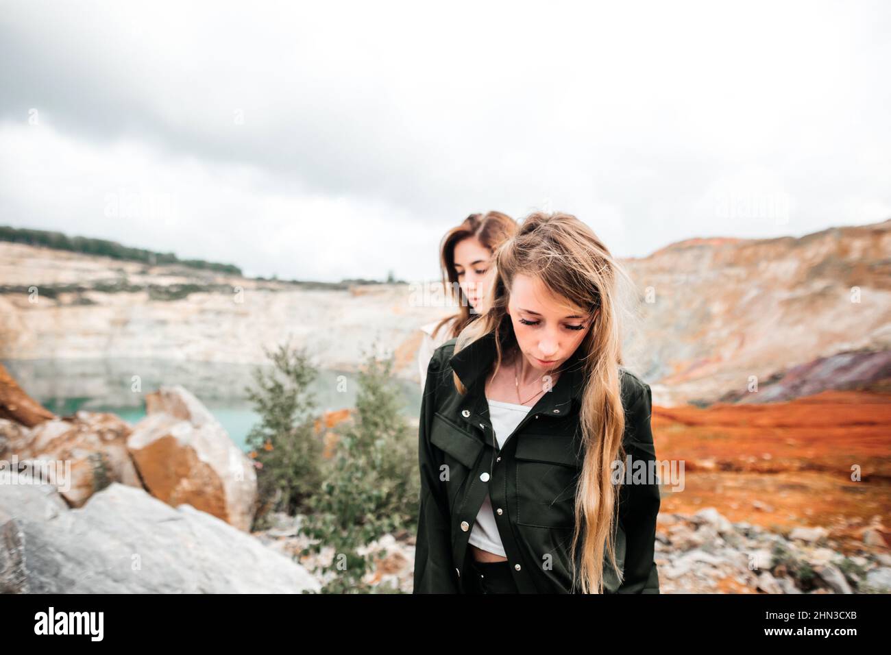 Girls in a post-apocalyptic place, a quarry with red earth and stones ...