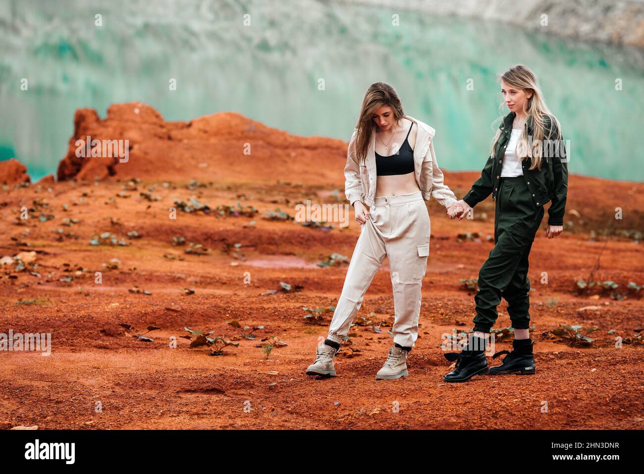 Girls in a post-apocalyptic place, a quarry with red earth and stones ...