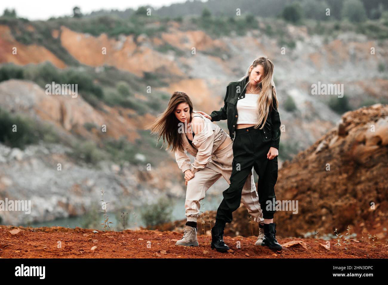 Girls in a post-apocalyptic place, a quarry with red earth and stones ...