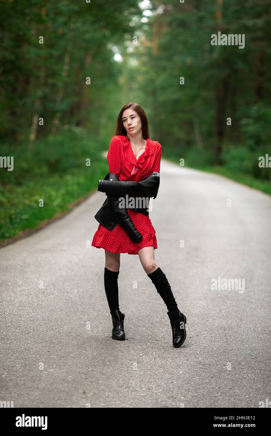 A girl in a light red airy dress, a leather jacket in a rockstyle on an ...