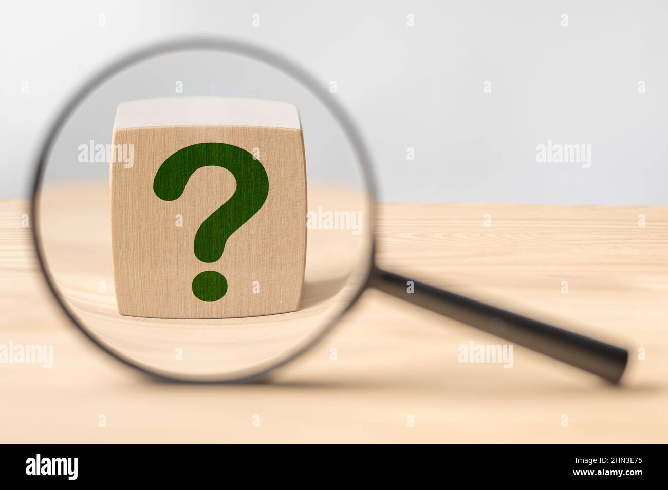 Magnifying glass with question mark in focus on wooden cube. Search for ...