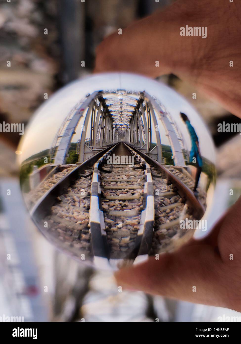 Vertical shot of a person holding a crystal ball with rail tracks ...