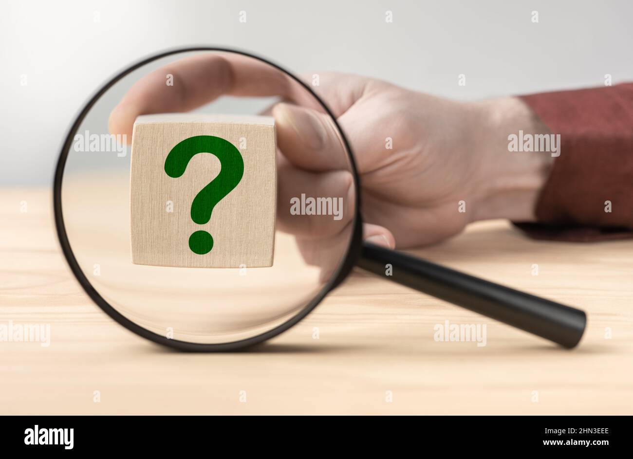 Hand holding question mark in front of magnifying glass. Search for an ...