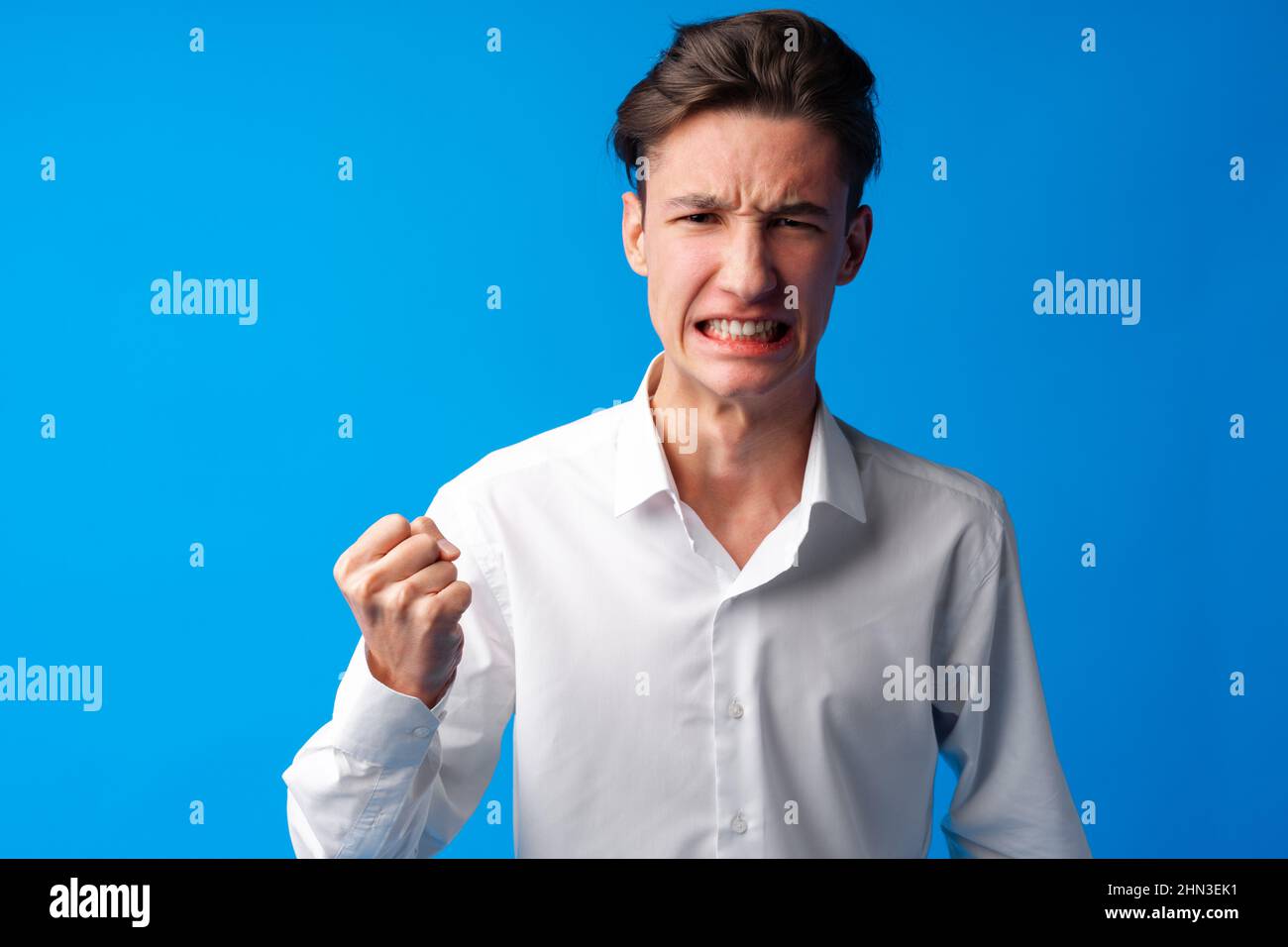Angry stressed teen boy with clenched fist on blue background Stock ...
