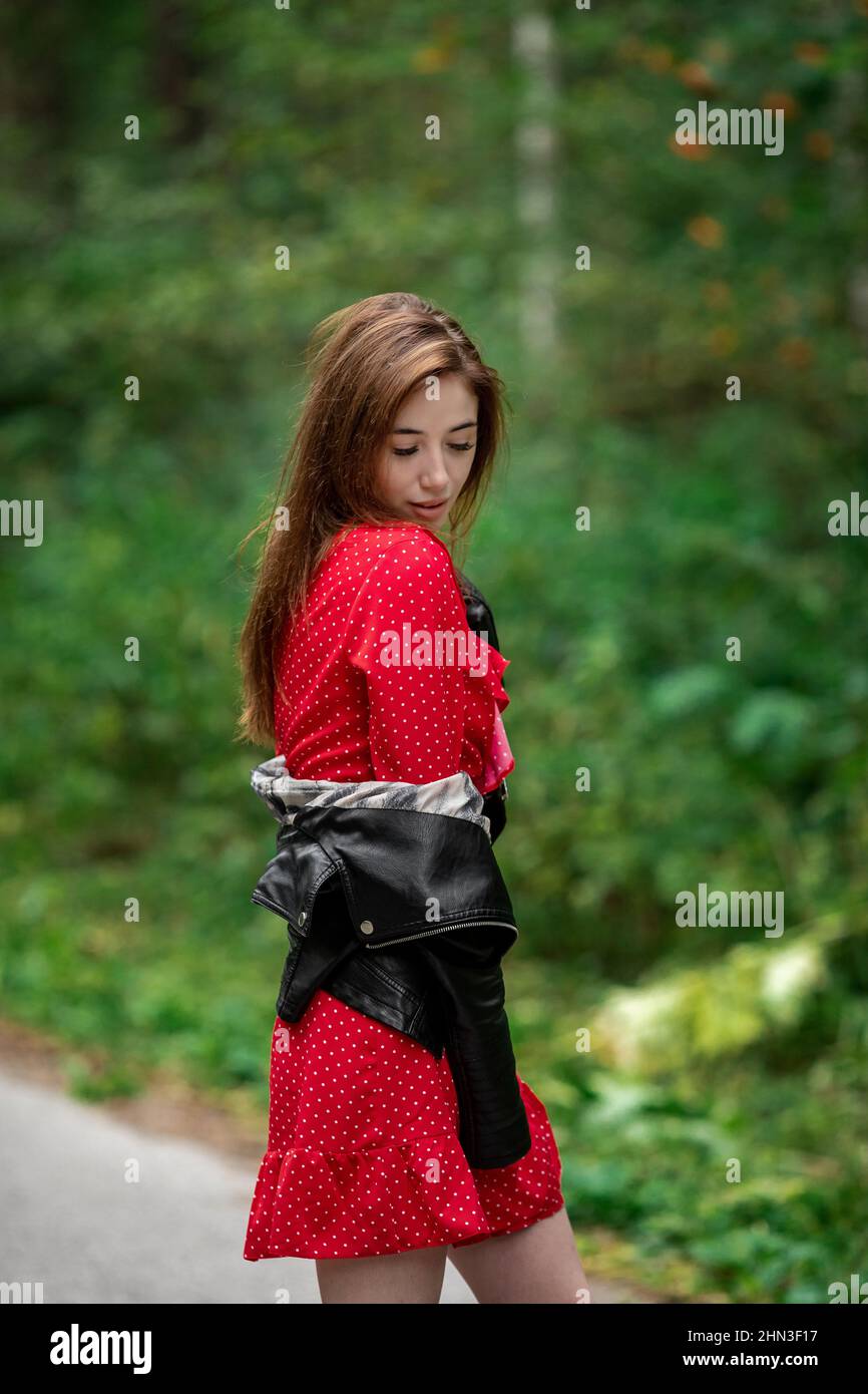 A girl in a light red airy dress, a leather jacket in a rockstyle on an ...